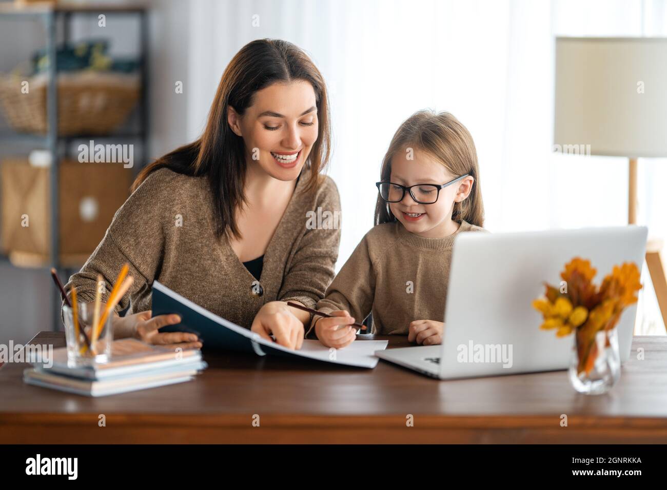Back to school. Happy child and adult are sitting at desk. Girl doing ...