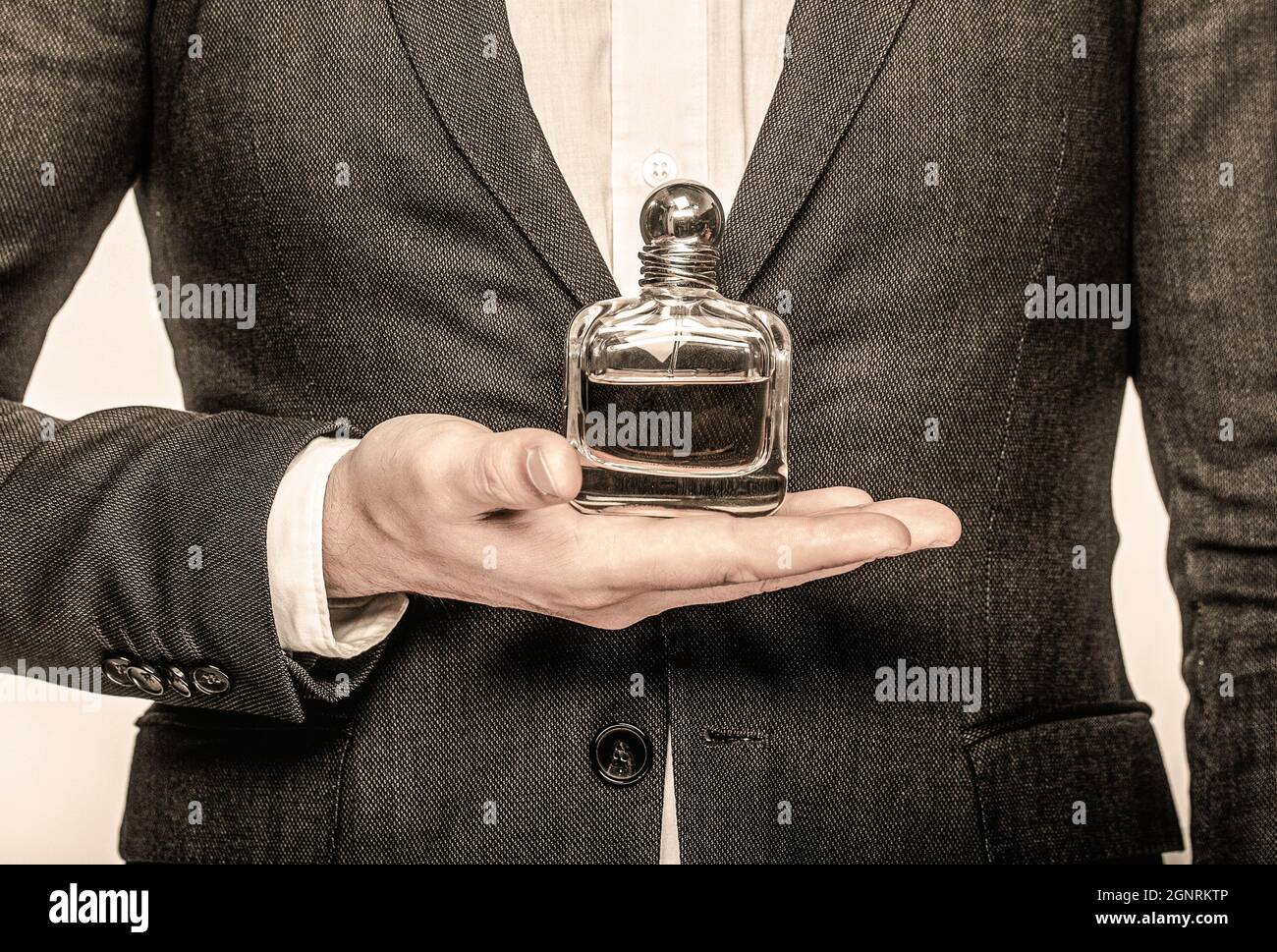 Man in a suit holding a bottle of perfume isolated on white background ...
