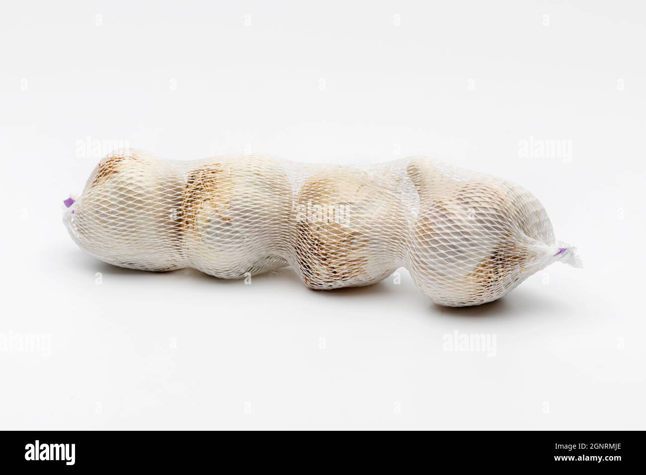 A net tube with four cloves of garlic in it Stock Photo - Alamy