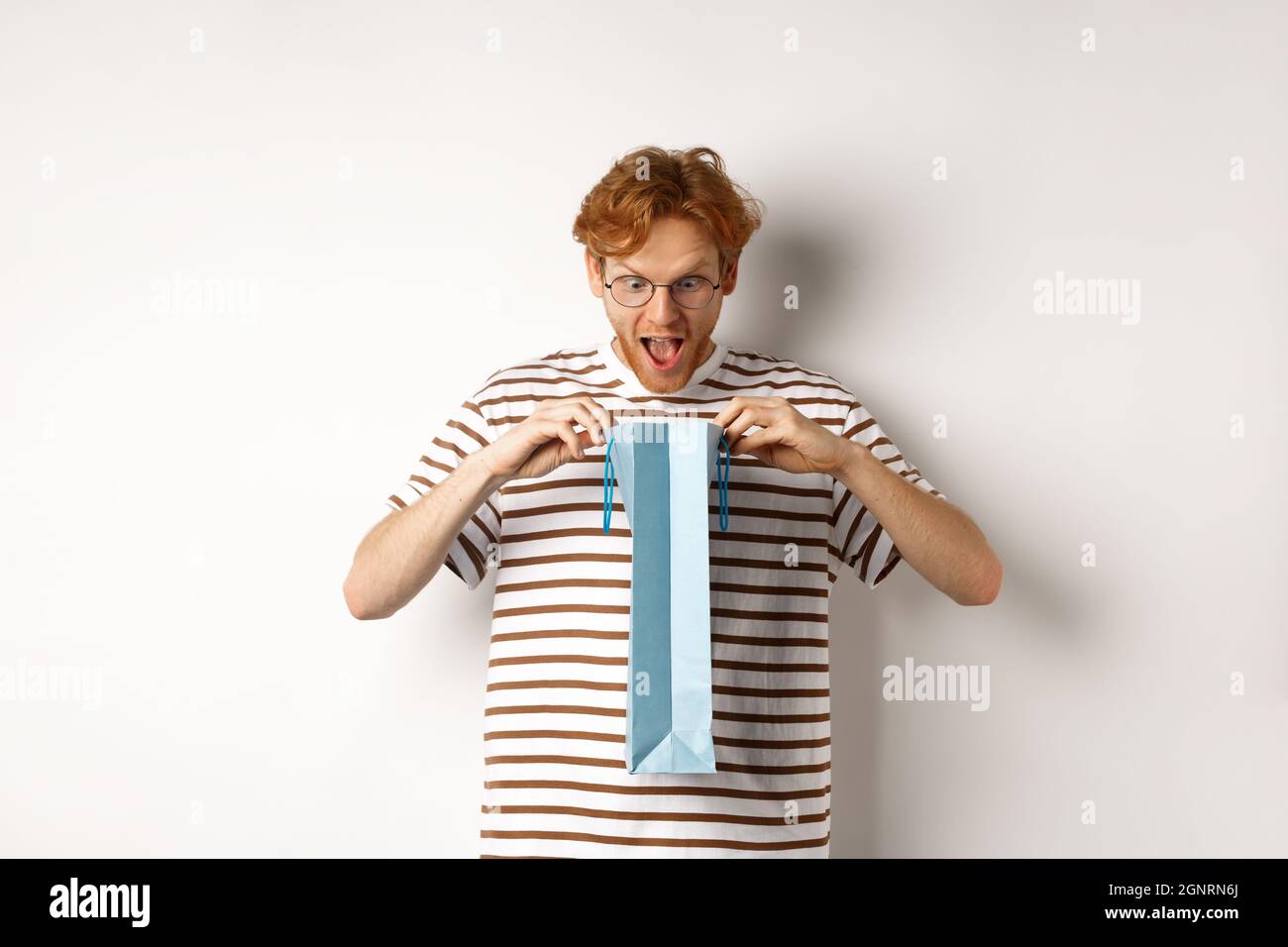 Surprised boyfriend open shopping bag with valentines day gift, staring ...