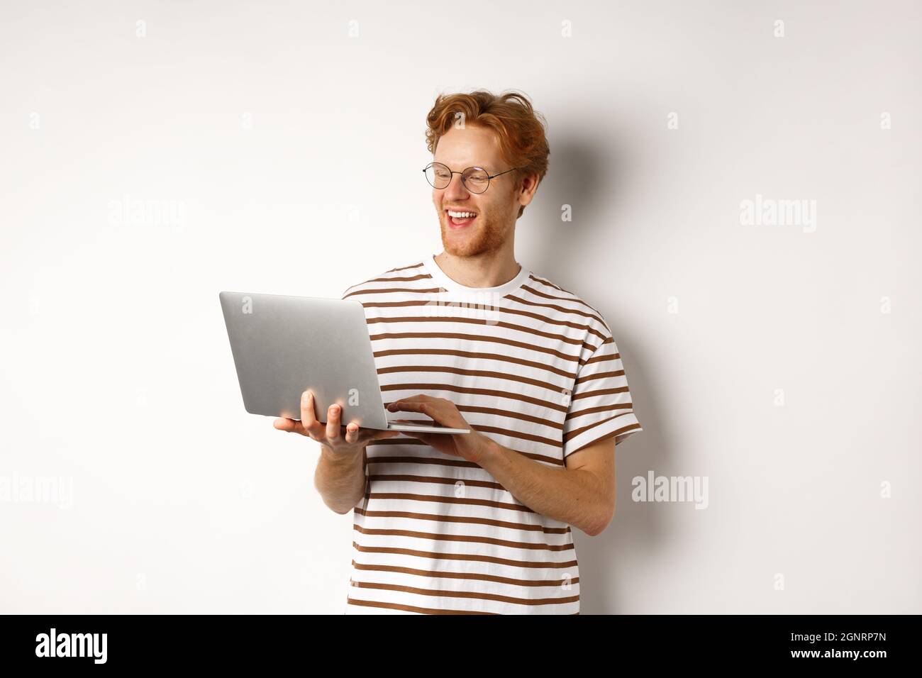 Handsome redhead man working freelance on laptop, smiling and looking ...