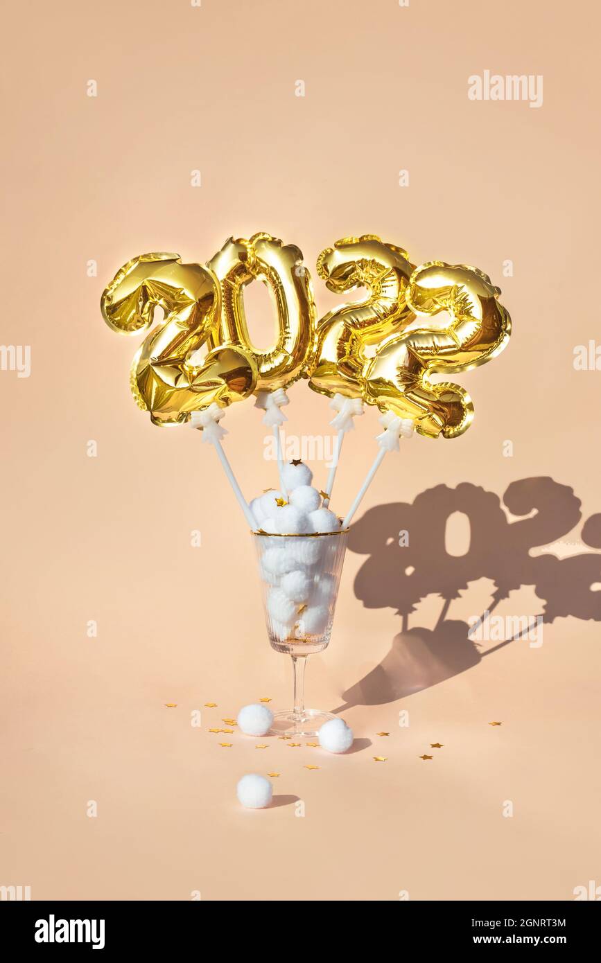 Gold balloons 2022 in a champagne glass, confetti. The concept of merry ...