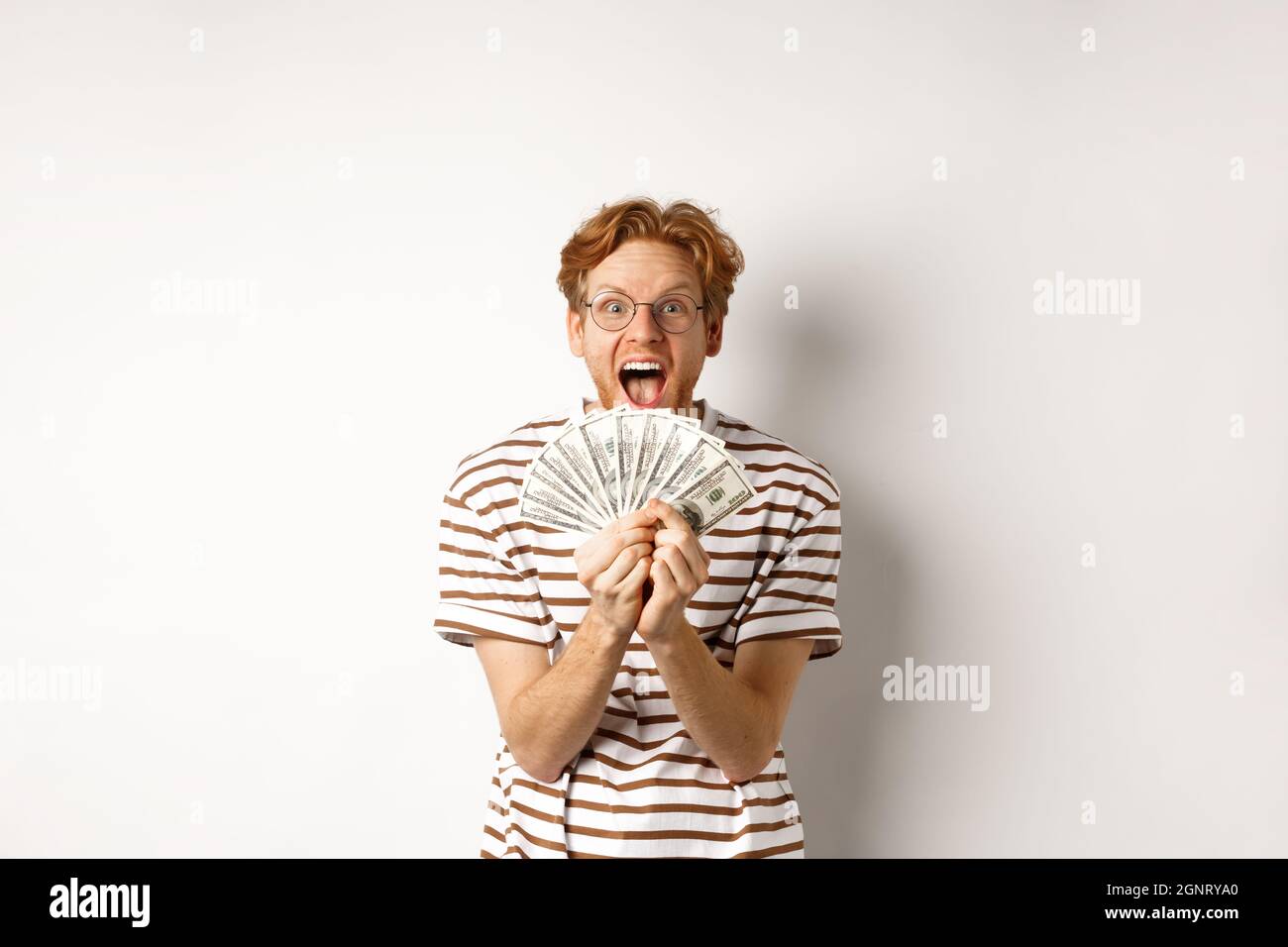 Lucky young man with red hair showing dollars, winning money and ...