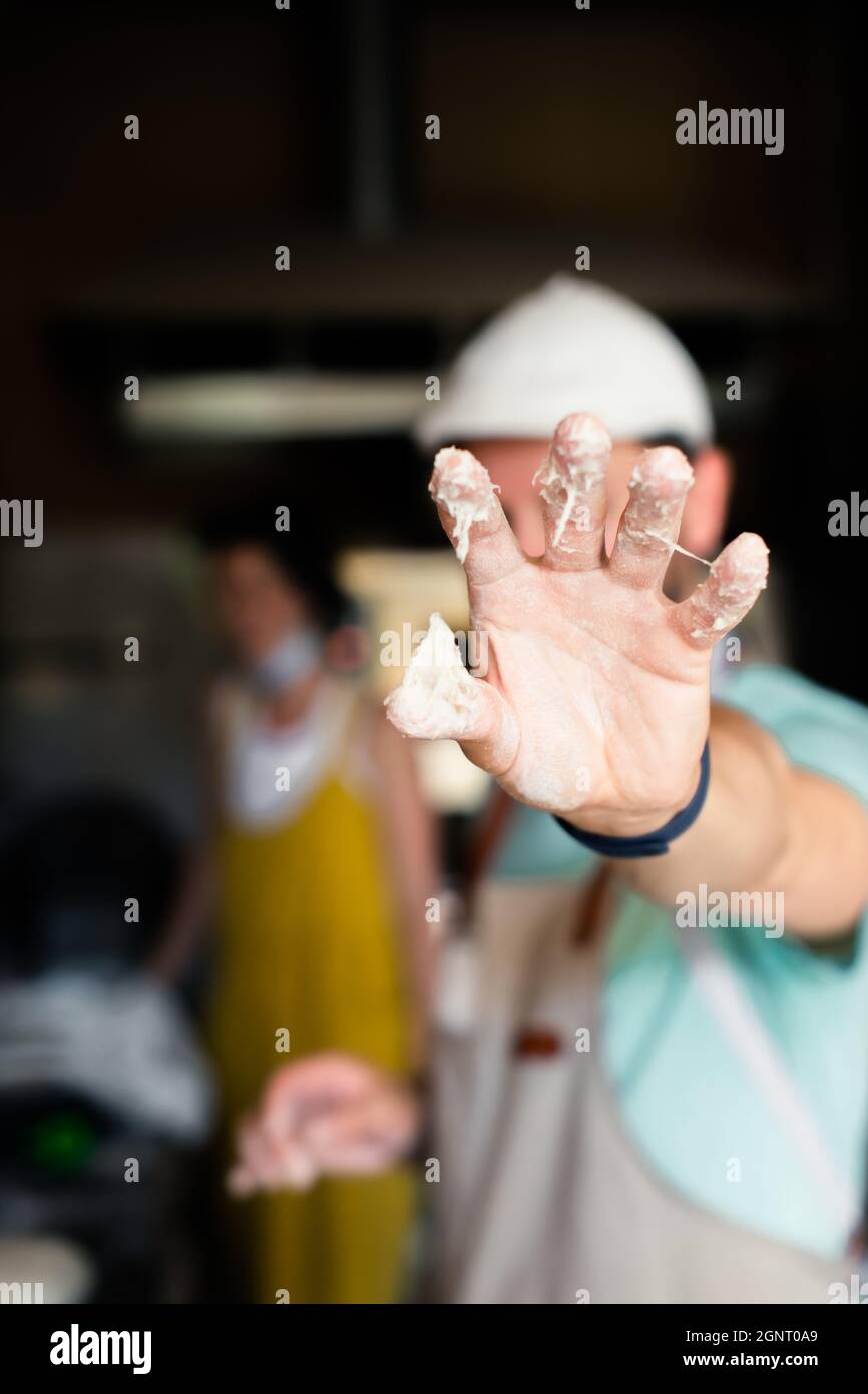 A man baker stretched out his hand in dough in front of the camera ...