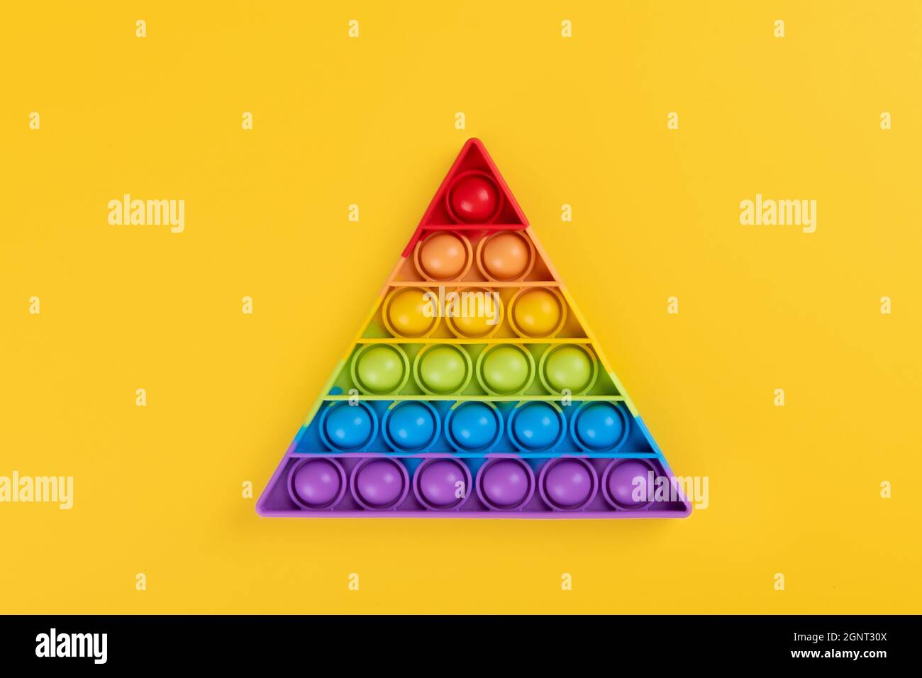 Bright rainbow toy antistress for children and adults on a yellow ...