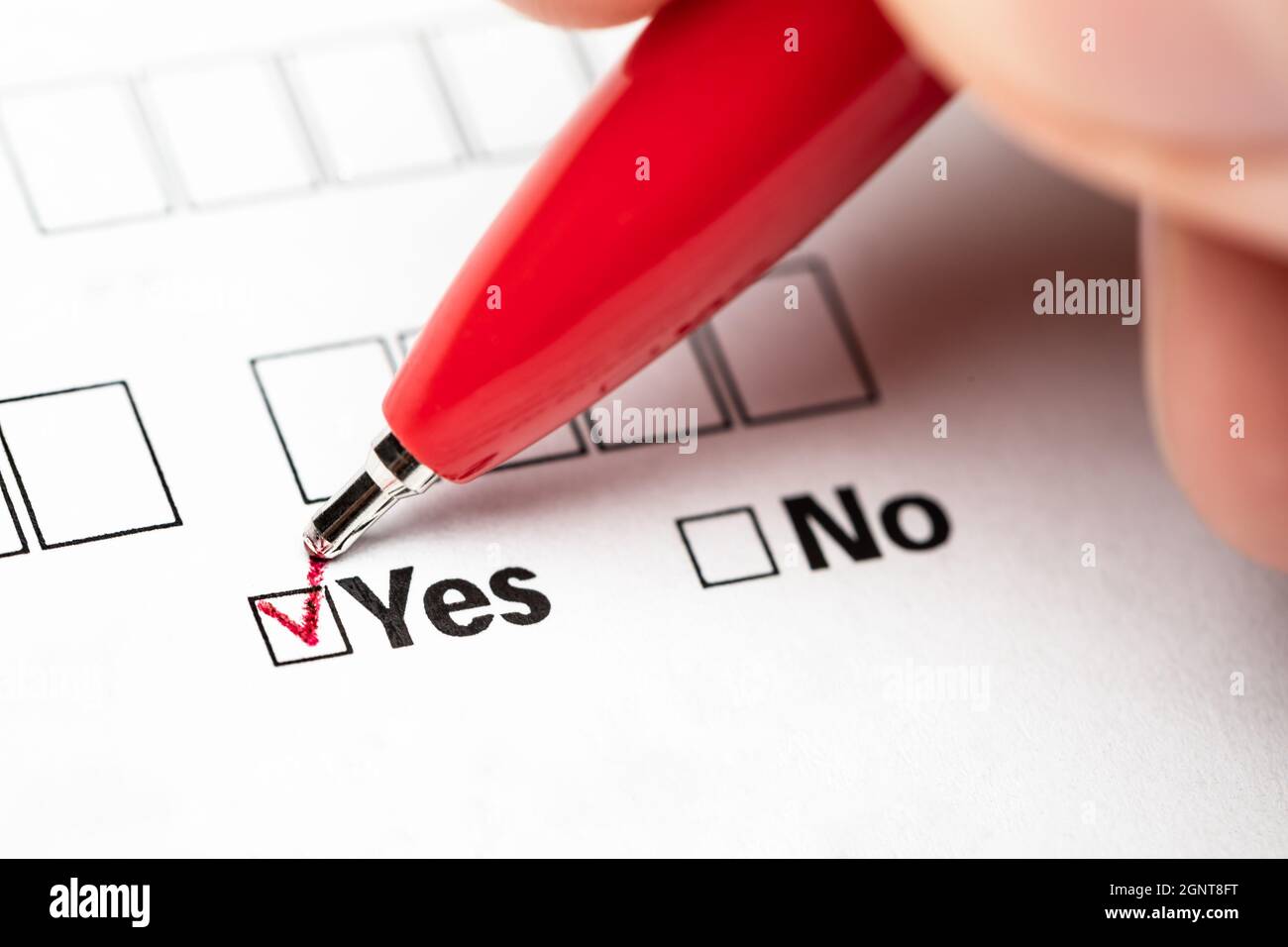 Person selecting Yes tickbox on a document form with red ballpoint pen ...