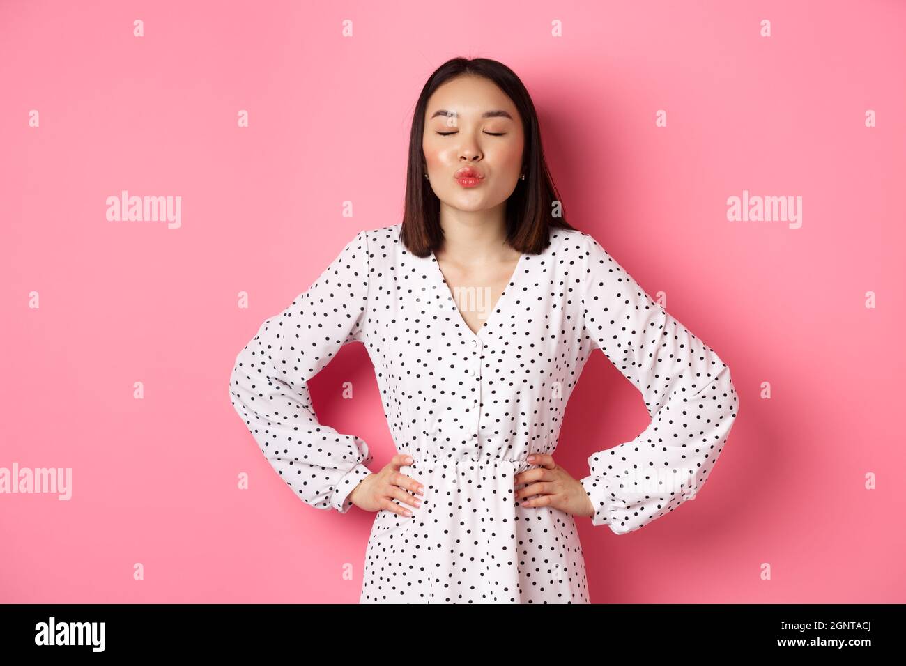Beautiful asian woman in dress pucker lips and close eyes, waiting for ...