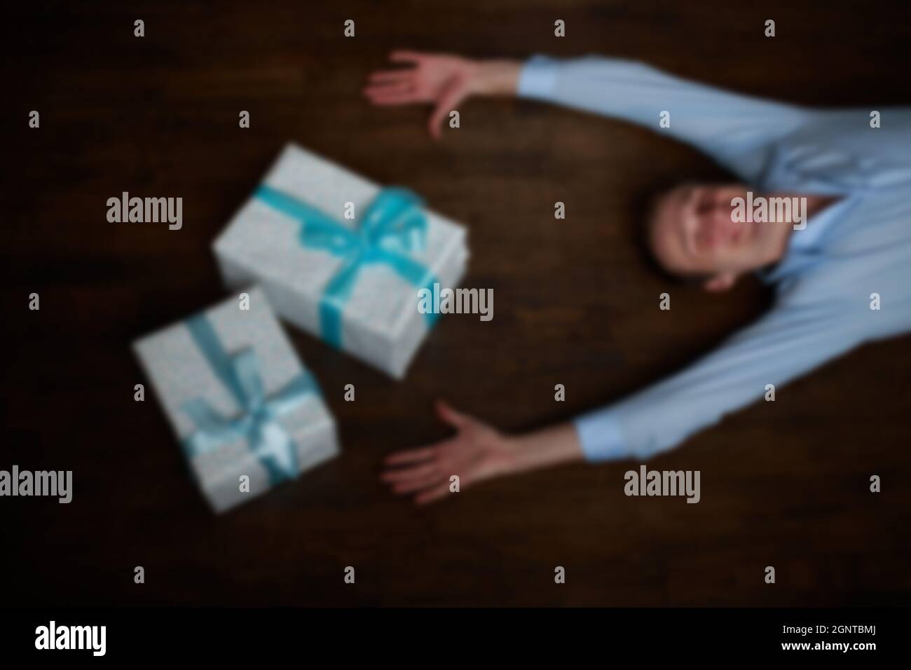 A man reaching for a gift. Young man lying on the floor in a blue shirt ...