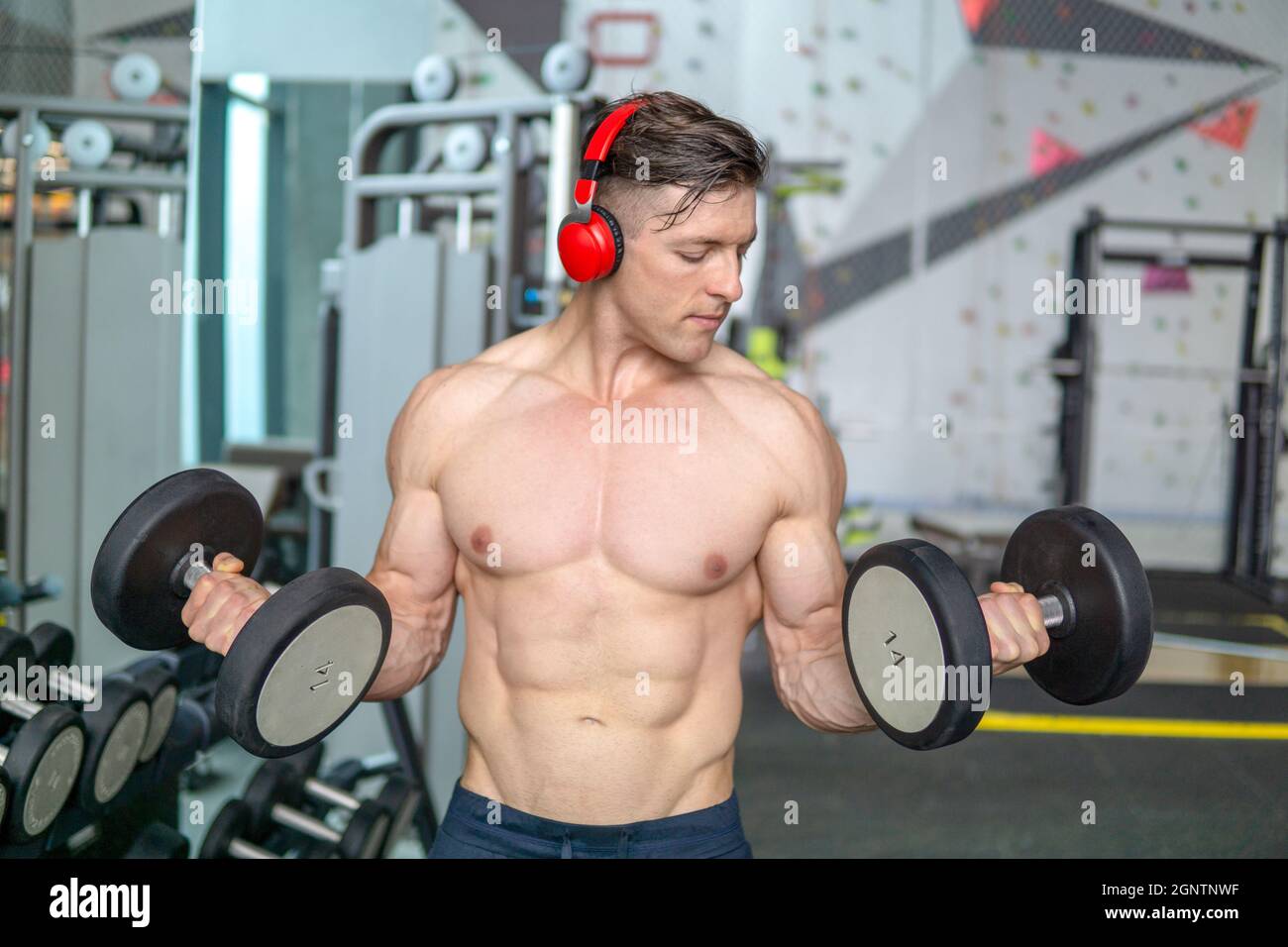 Muscular guy workout his biceps and listens to music Stock Photo - Alamy