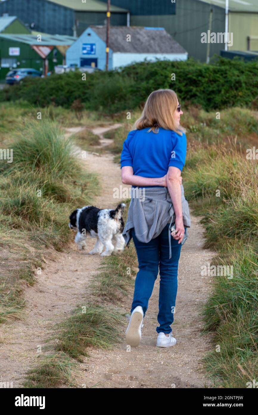 middle-aged woman walking a dog along a country lane wearing a t-shirt ...