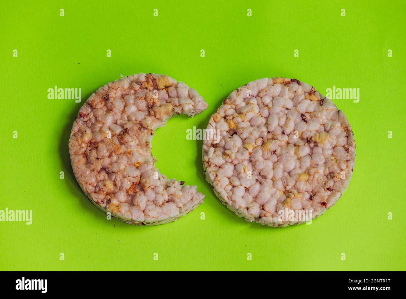 A whole rice loaf and a bitten moon-shaped loaf on a green background ...