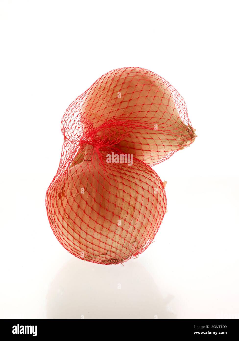Culinary green onions in red net bag against plain light background ...