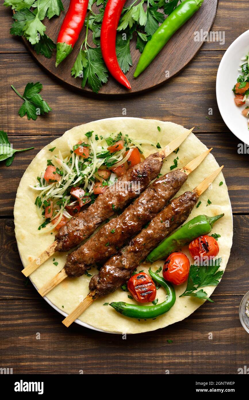 Turkish Adana Kebab with fresh vegetables on flatbread over wooden ...