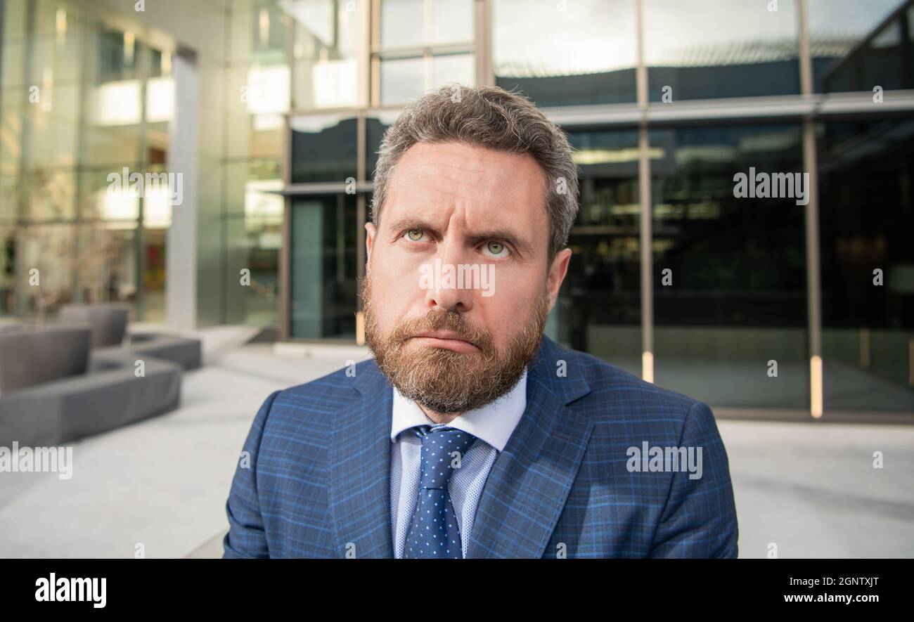 confused face of entrepreneur in businesslike suit outside the office ...