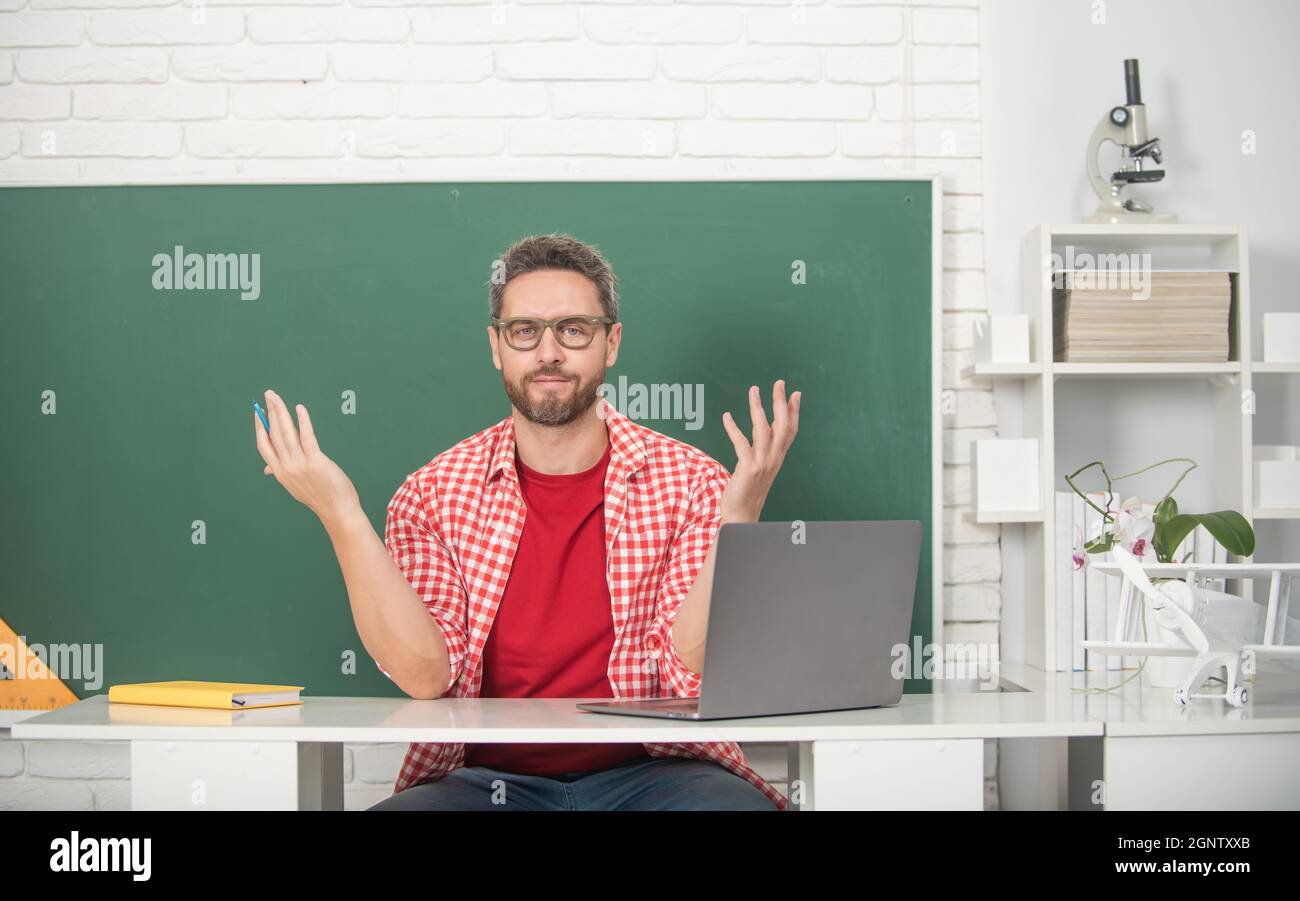 smiling adult man tutor sitting in classroom at blackboard, education ...