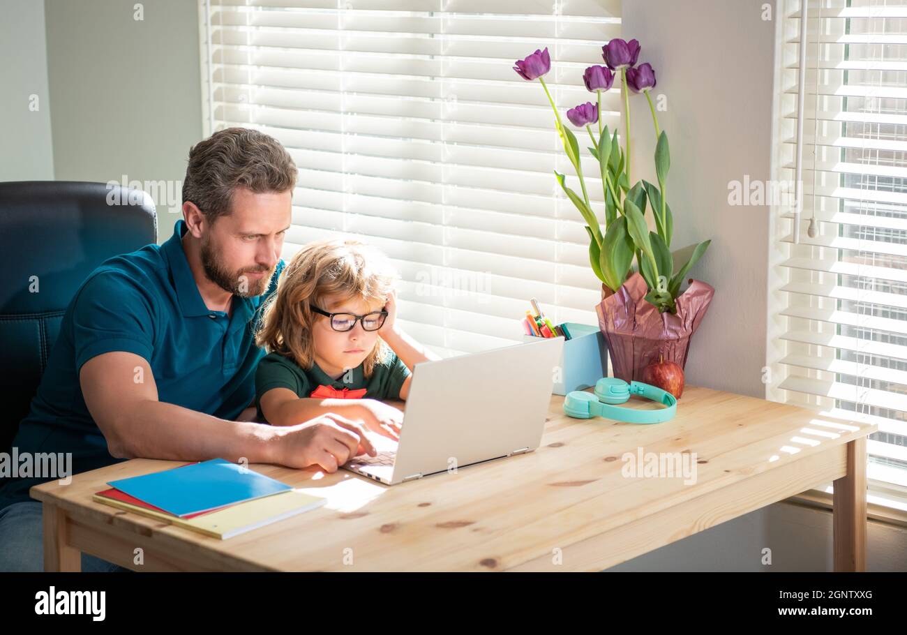 dad helping his school son child in glasses study with computer at home ...
