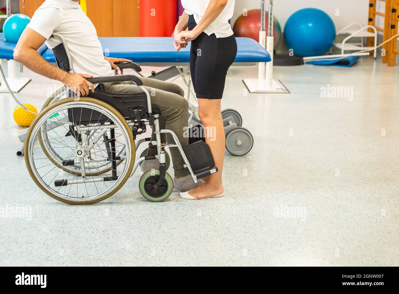 Disabled patient and female physiotherapist, exercise standing up and ...