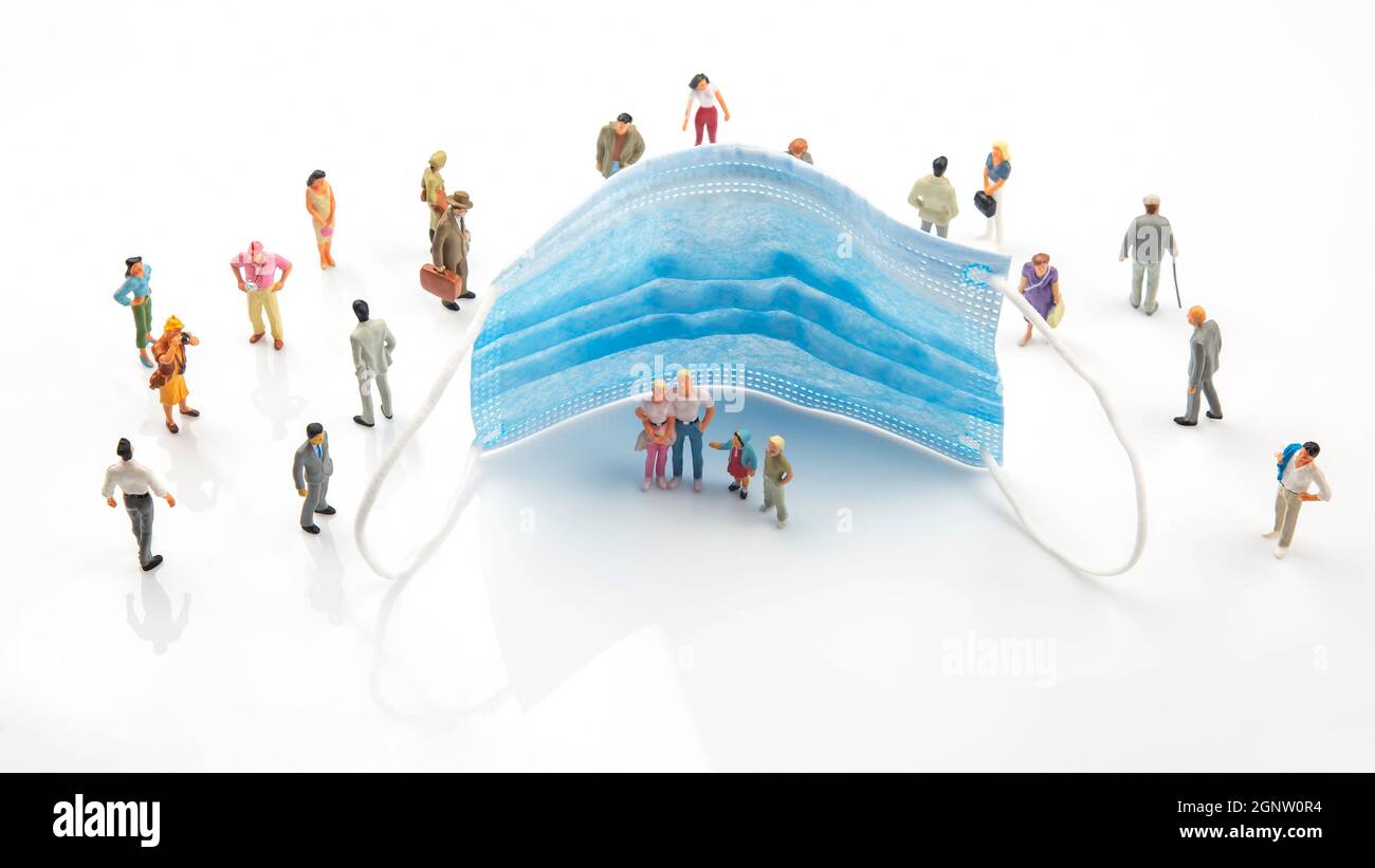 miniature people. figurines of people next to a medical mask. the ...