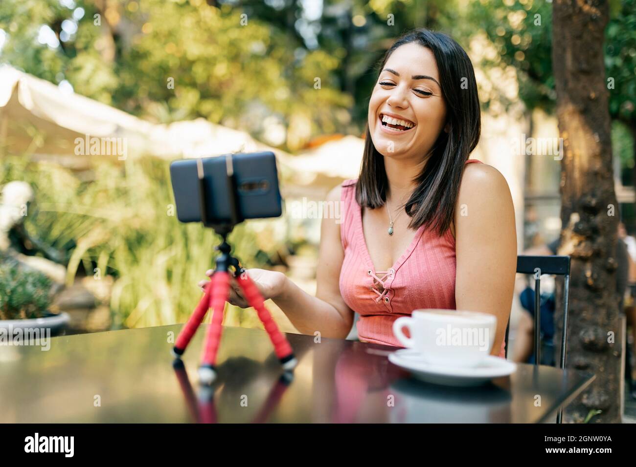 Happy woman recording video for her vlog on mobile phone at cafe ...