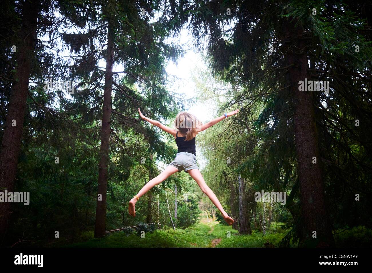 Young girl flying in the air in the woods. Jumping for freedom Stock ...