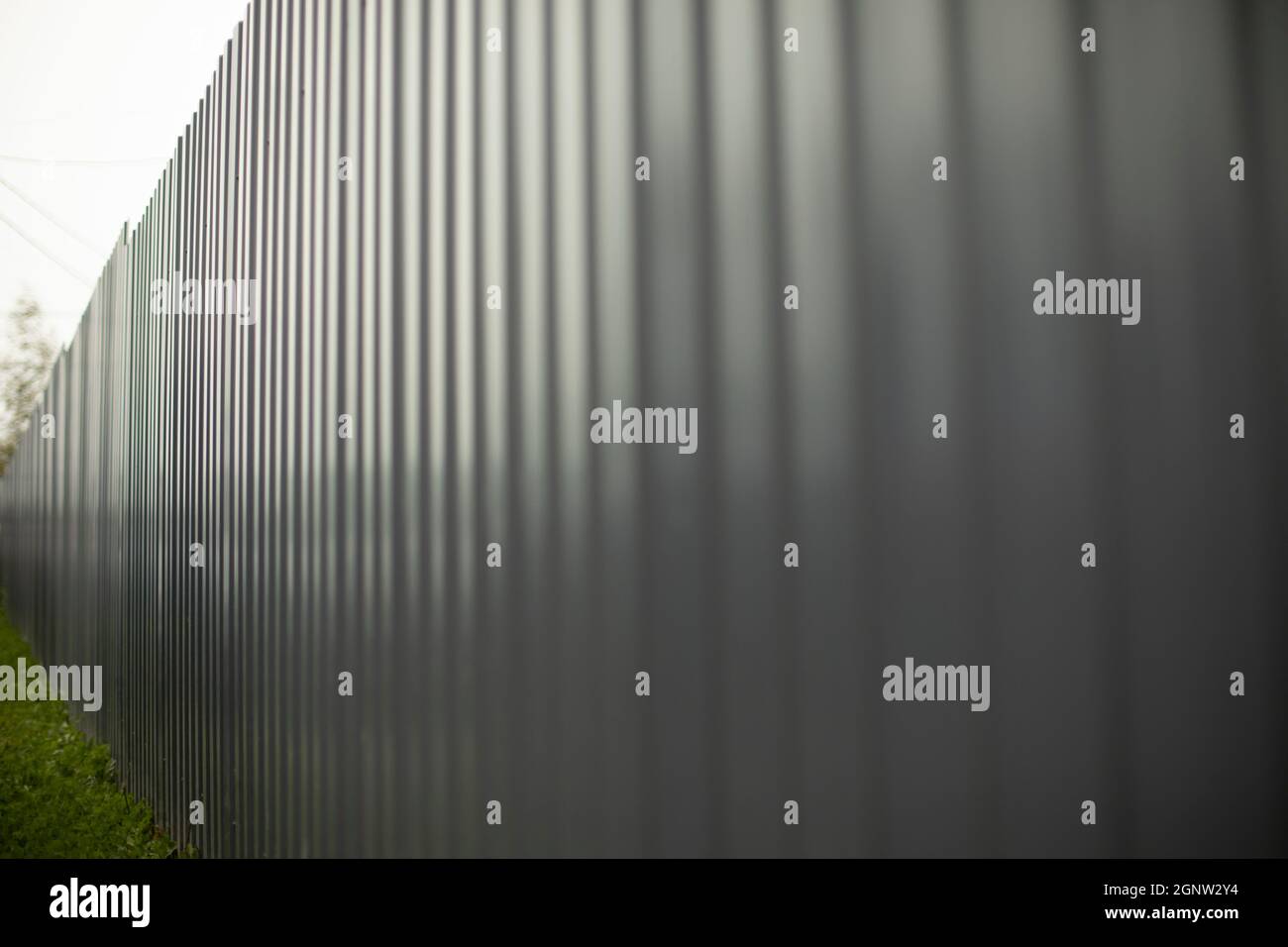 Grey fence made of metal. Solid high fence. Profiled metal is used in ...