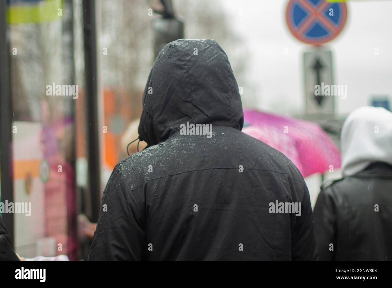People from the back in the rain. Hooded people walk towards the bus ...