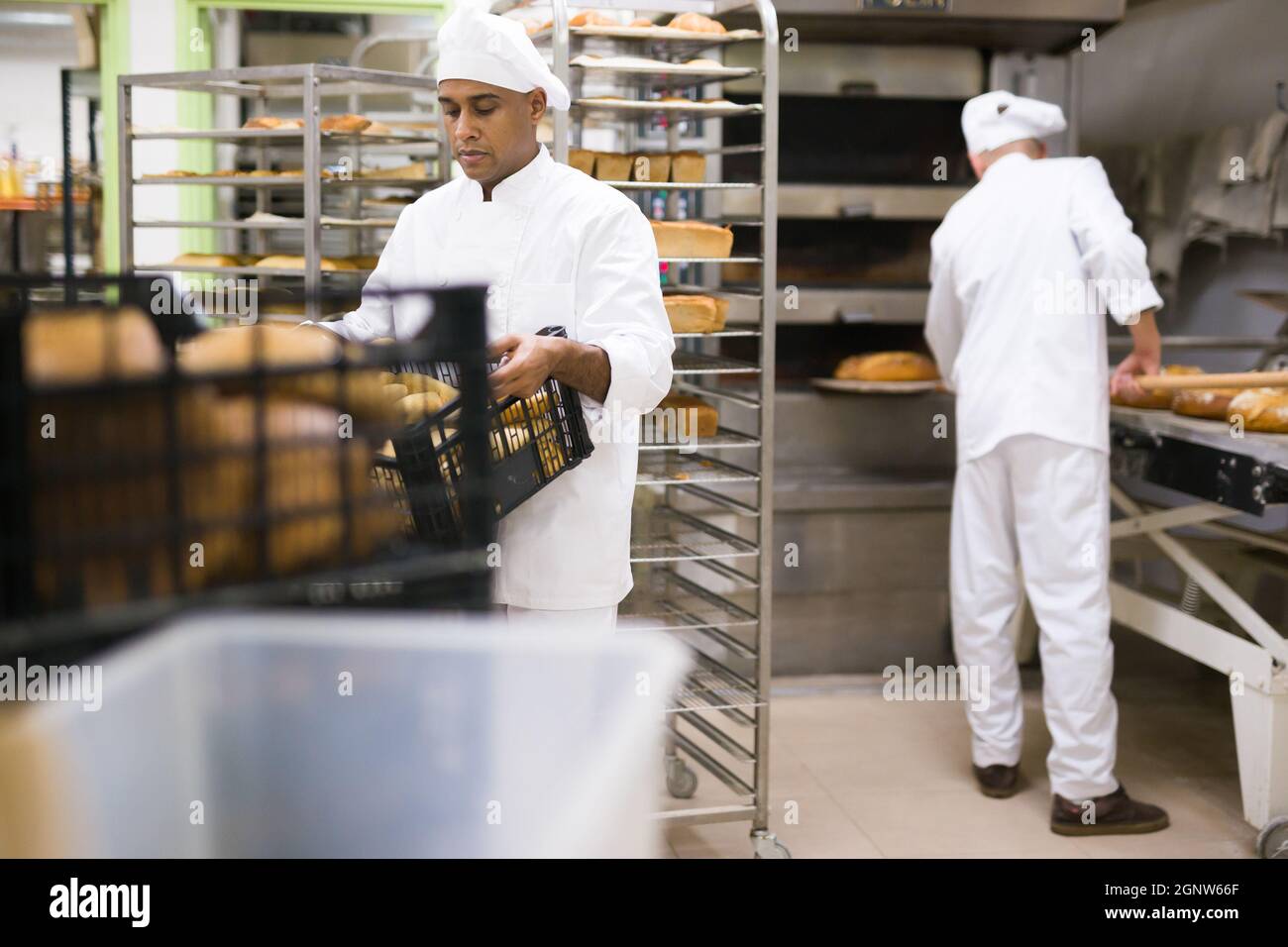 Male baker holding crate with baked bread Stock Photo - Alamy