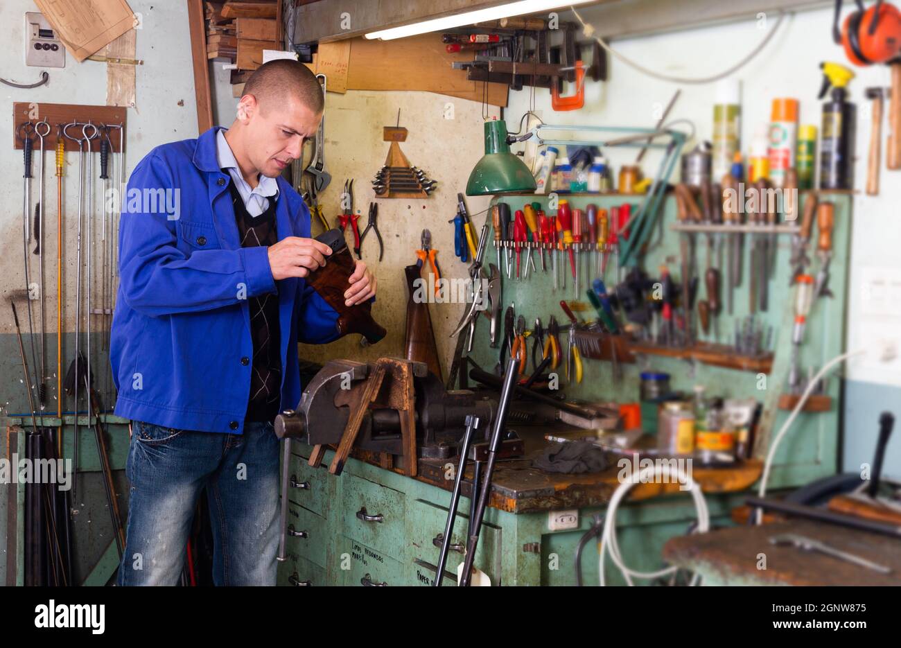 Professional craftsman repairing and assembling shotgun in weapons ...