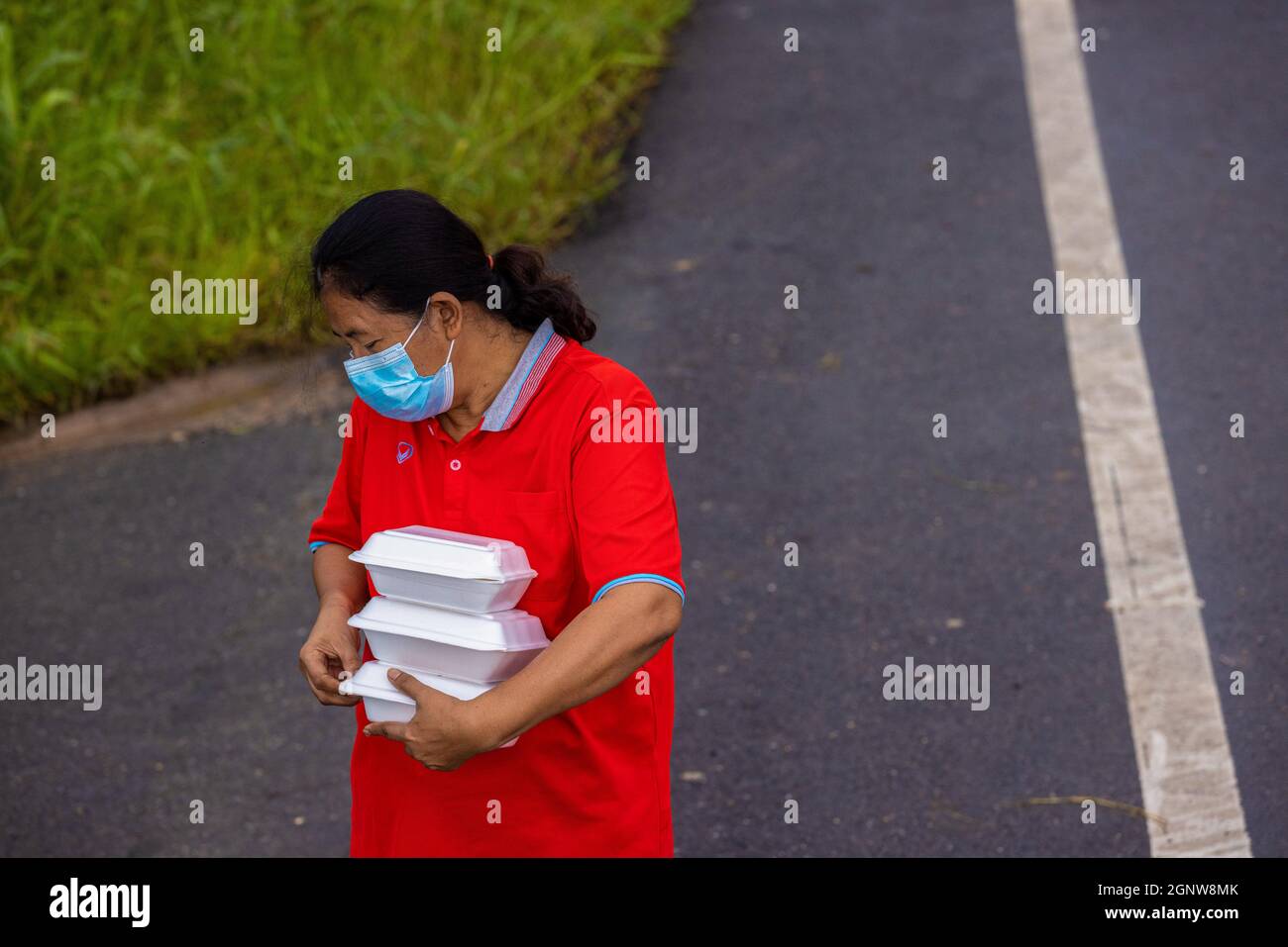 A woman is seen carrying packets of food donated to her after being ...