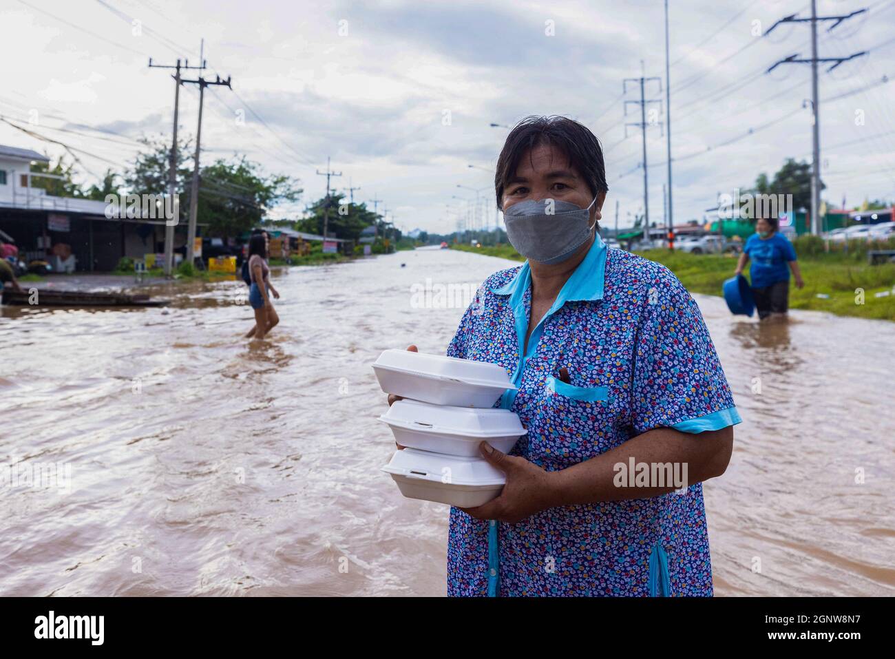 A woman is seen carrying packets of food donated to her after being ...