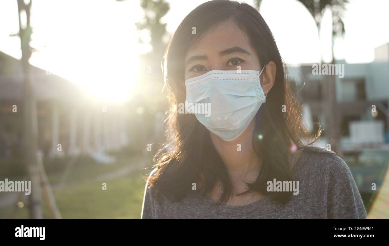 Coronavirus. Asian woman putting on a medical disposable mask to avoid ...