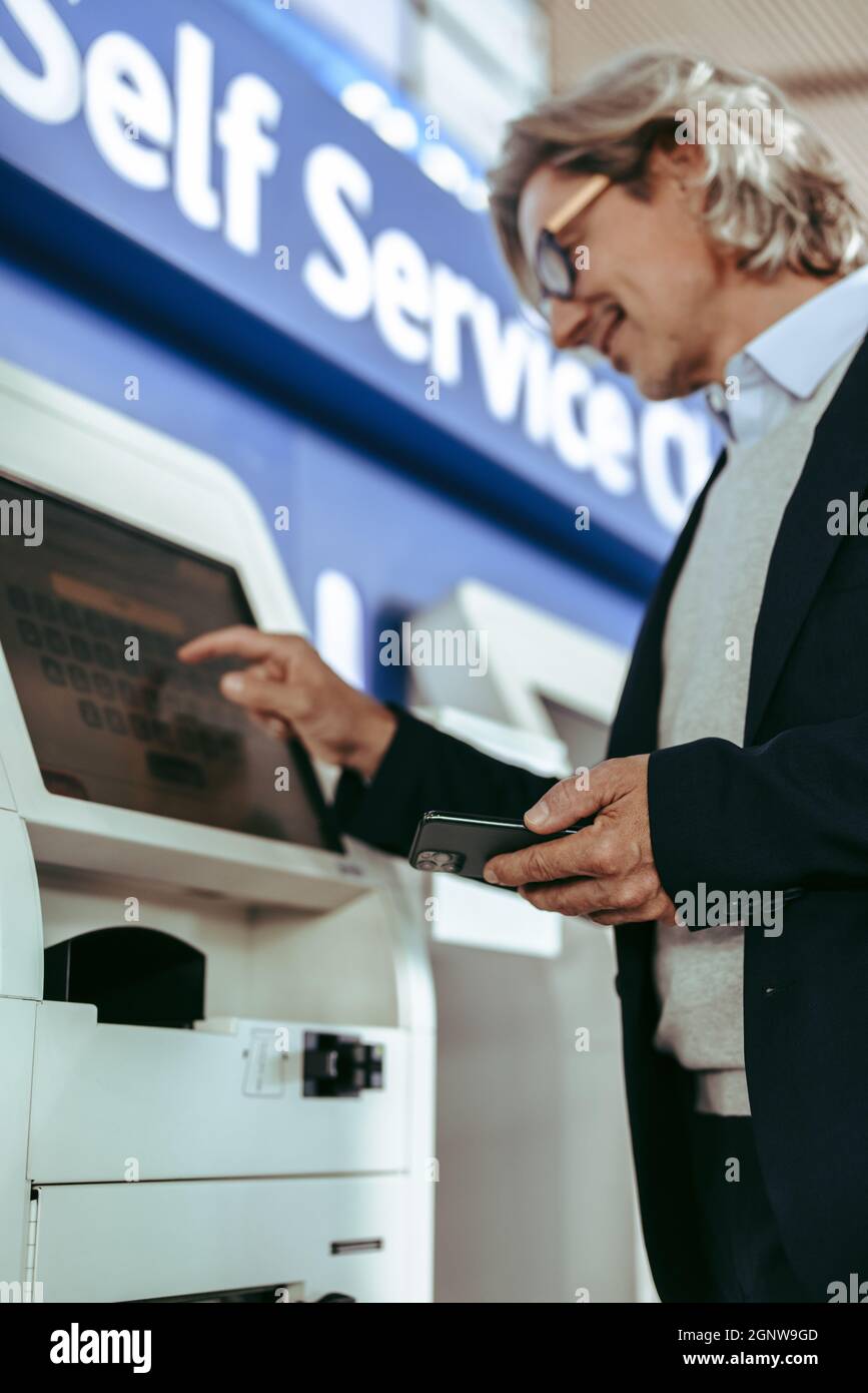 Low angle view of a man using self service check-in machine at airport ...