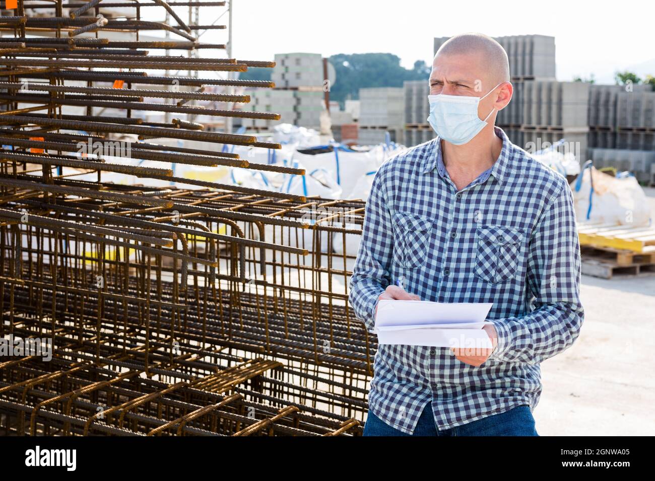 Worker in mask with checklist collecting order at hardware store Stock ...