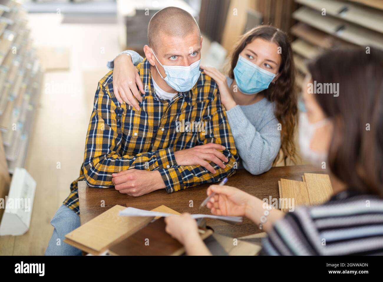 Salesman offering laminate flooring to woman and man in masks Stock ...