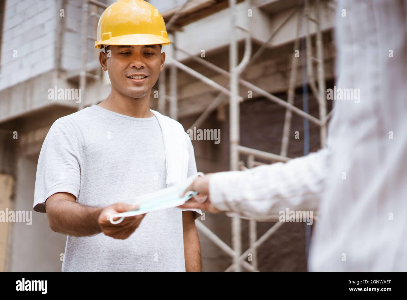 construction worker given a mask while working on a site project Stock ...