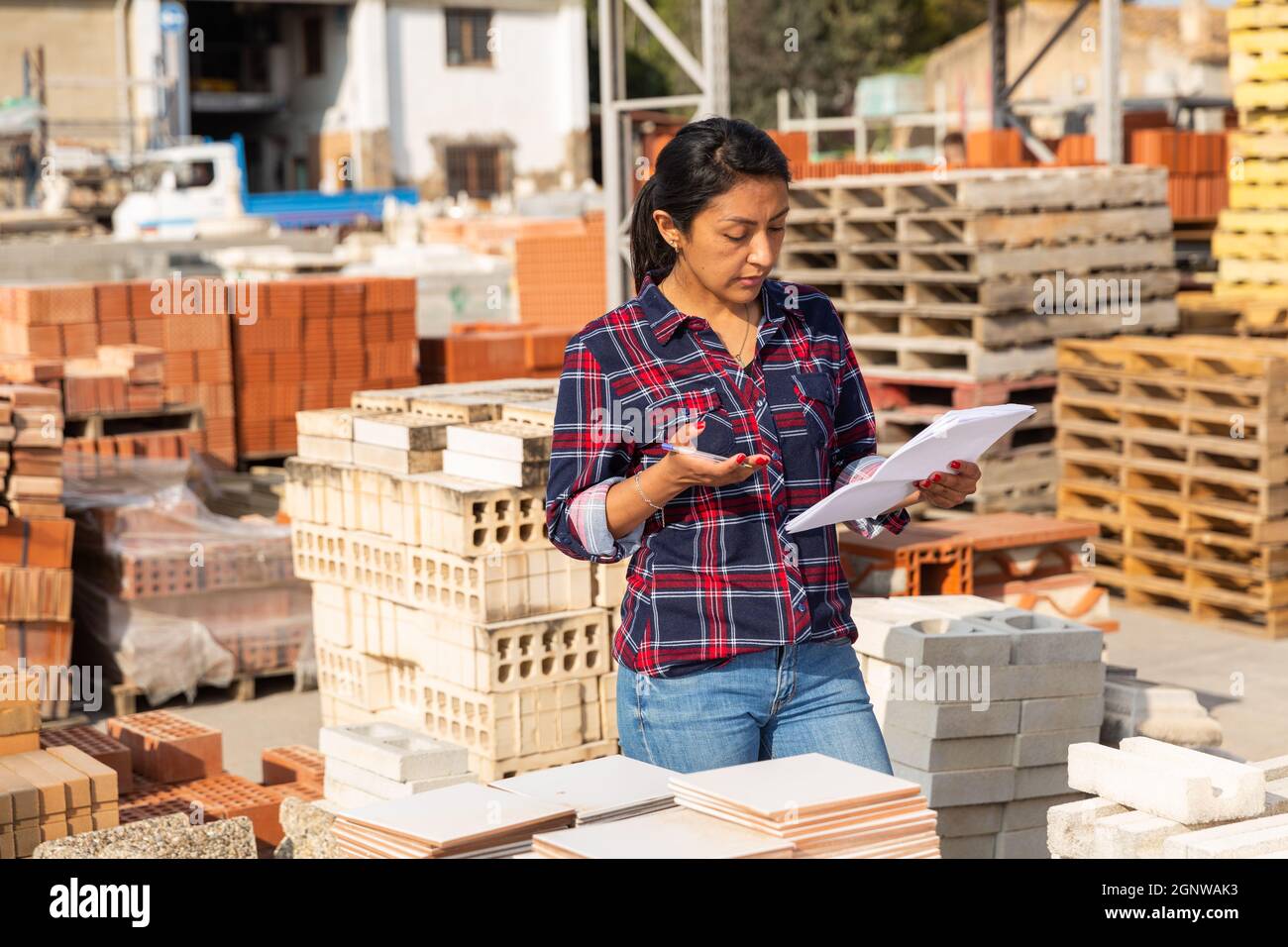 Woman manager keeps records of building materials in the open area of ...