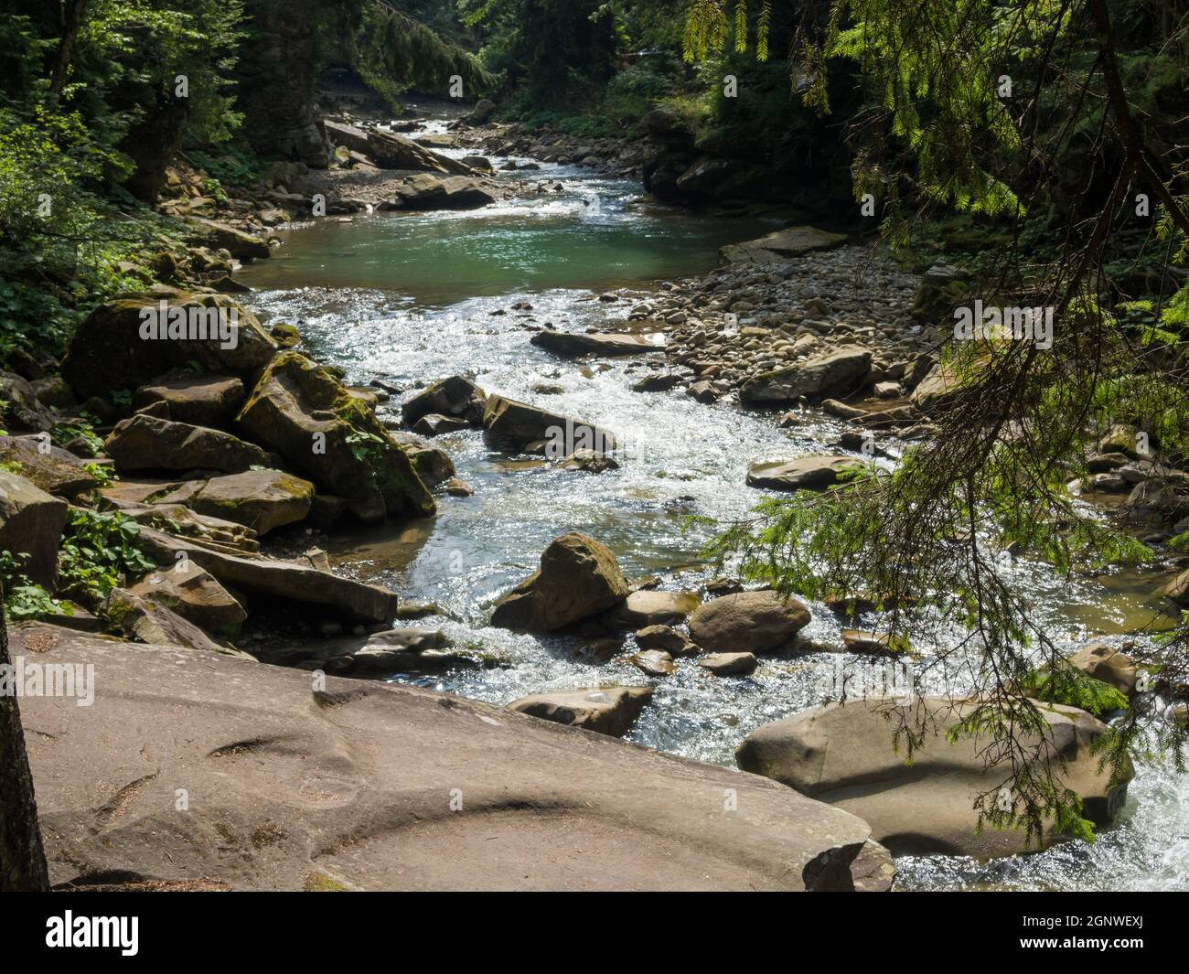 Small river flowing rapidly and vividly through its wild stony valley ...