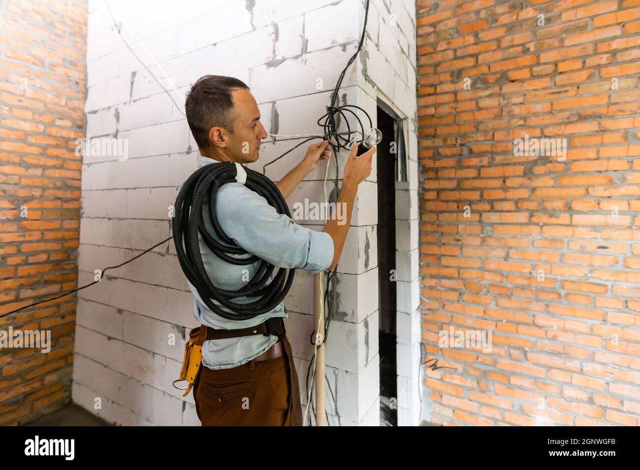repairman in overalls wearing tool belt standing in building ...