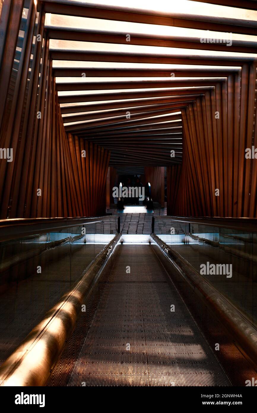 Escalator inside an abstract modern building with a wooden slat ceiling ...