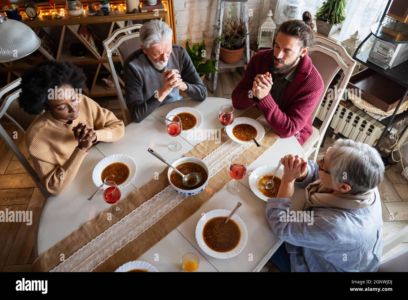 Happy multiethnic family praying before meal at home together. People ...