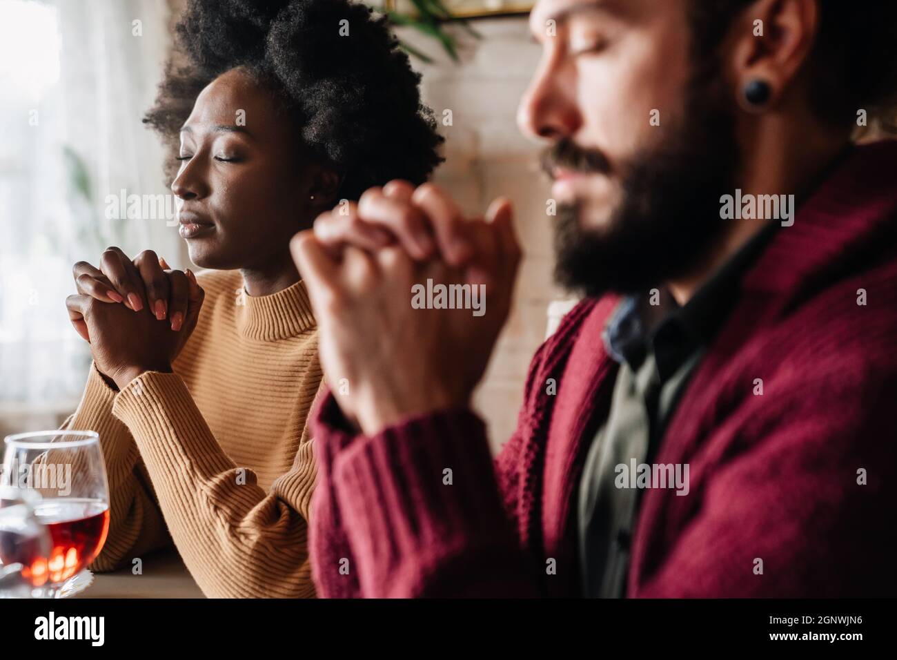 Young multiethnic couple praying to Lord to bless their food and day ...