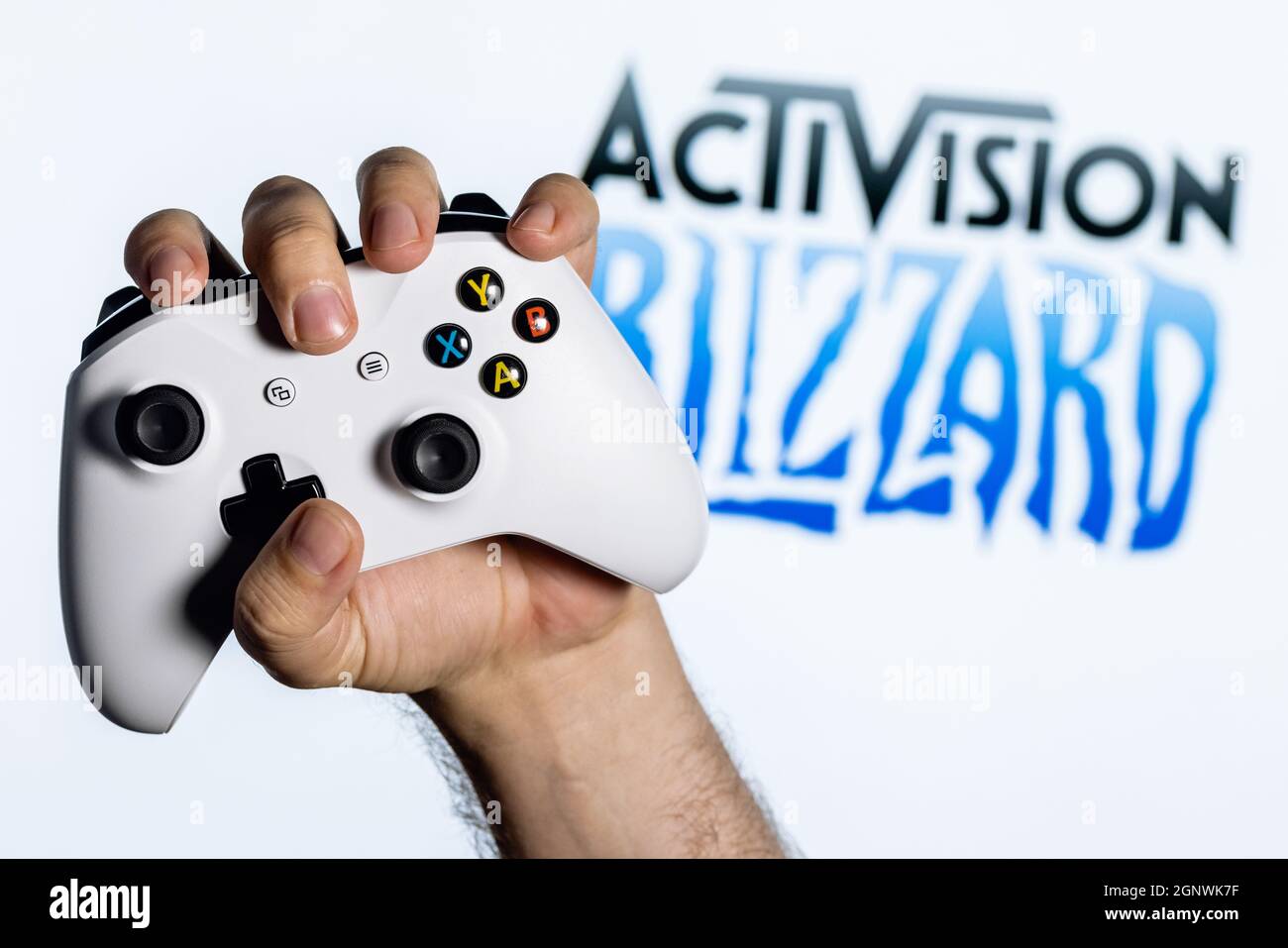 A gamepad clutched in the hand on the white background with the logo of ...