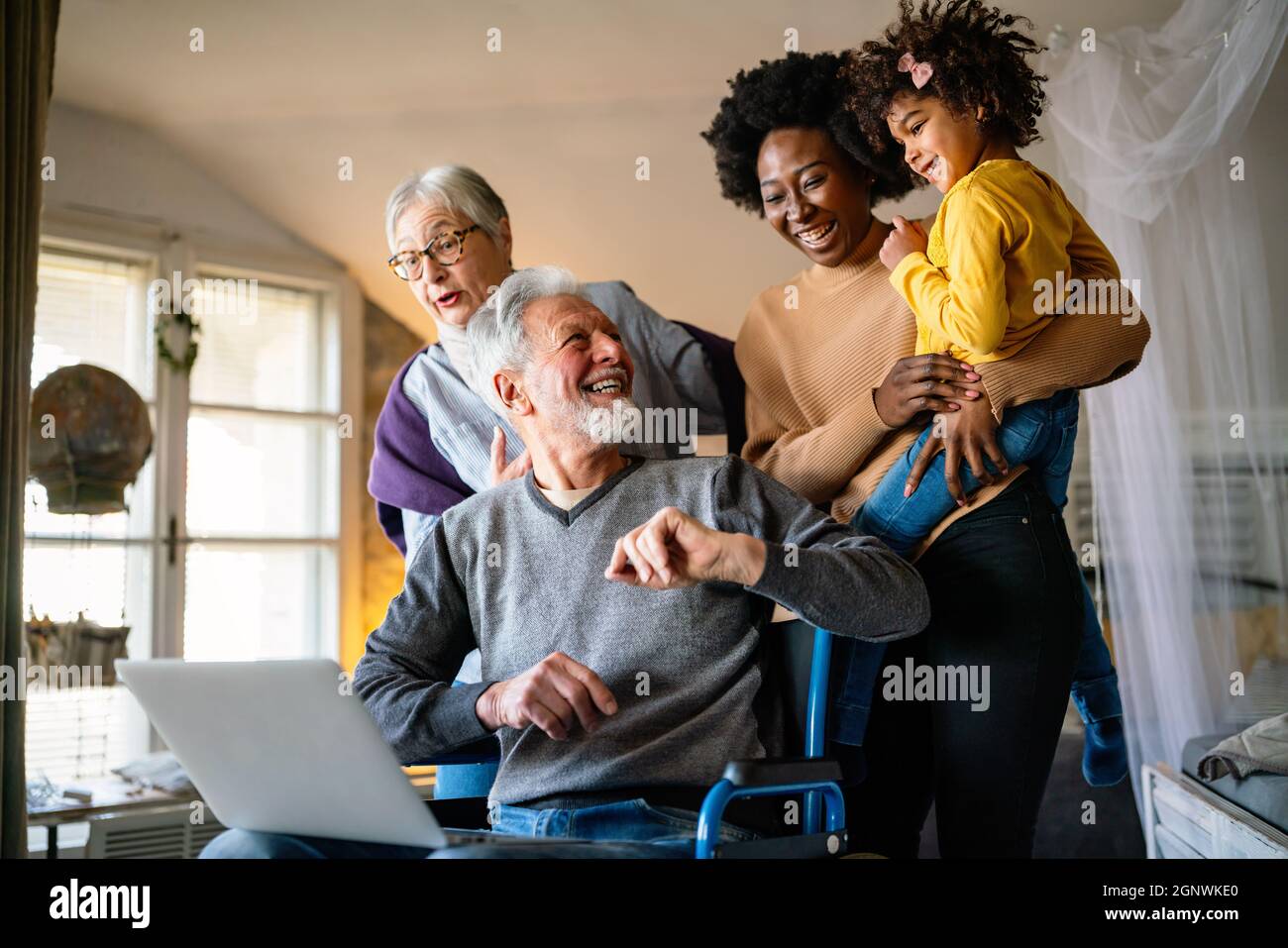 Happy multi-generation family gathering around notebbok and having fun ...