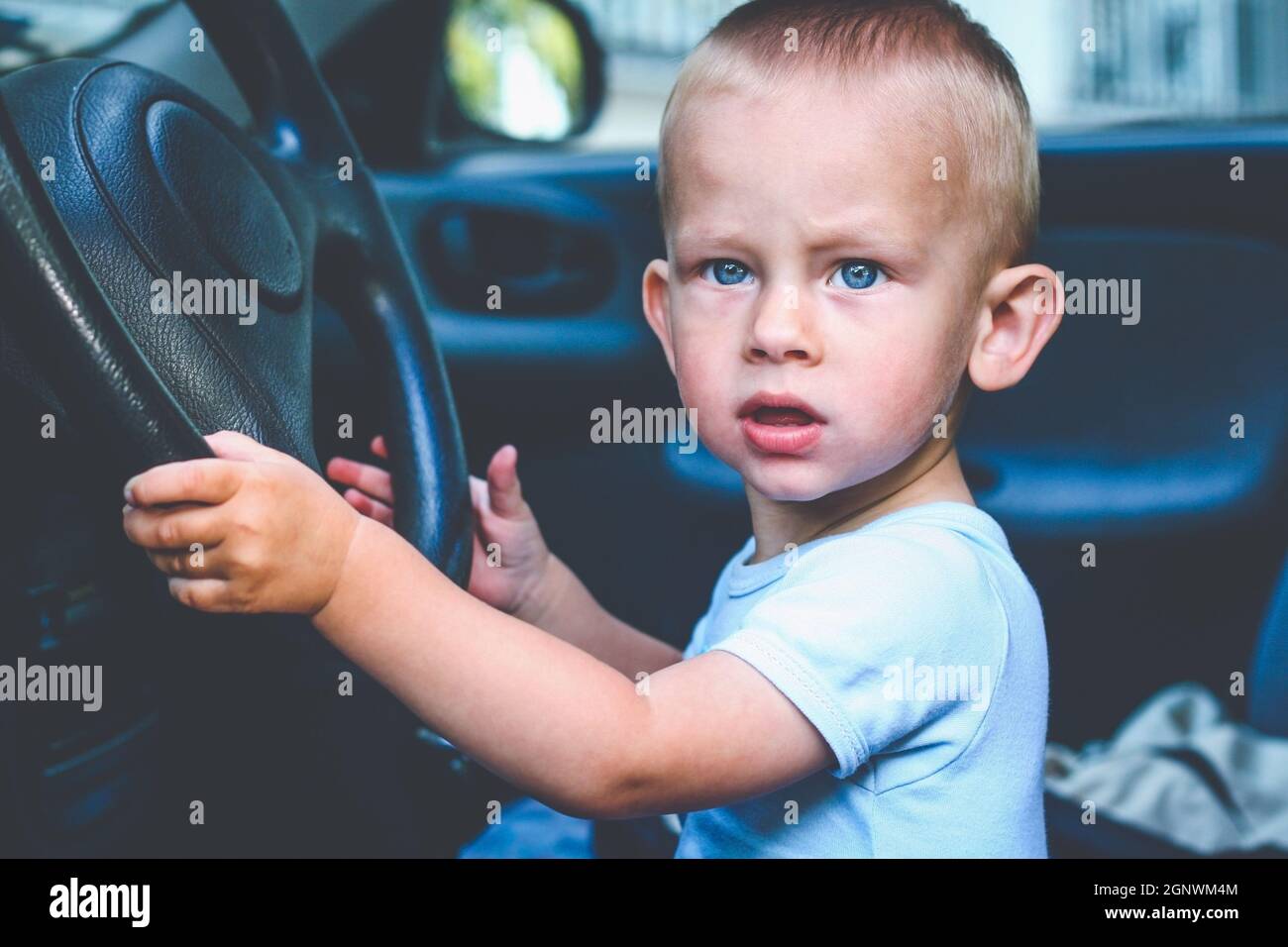 One year old baby boy sit behind the wheel and pretend driving car ...