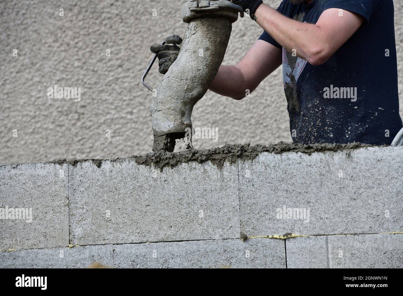 A concrete worker on a construction site concretes walls using a ...