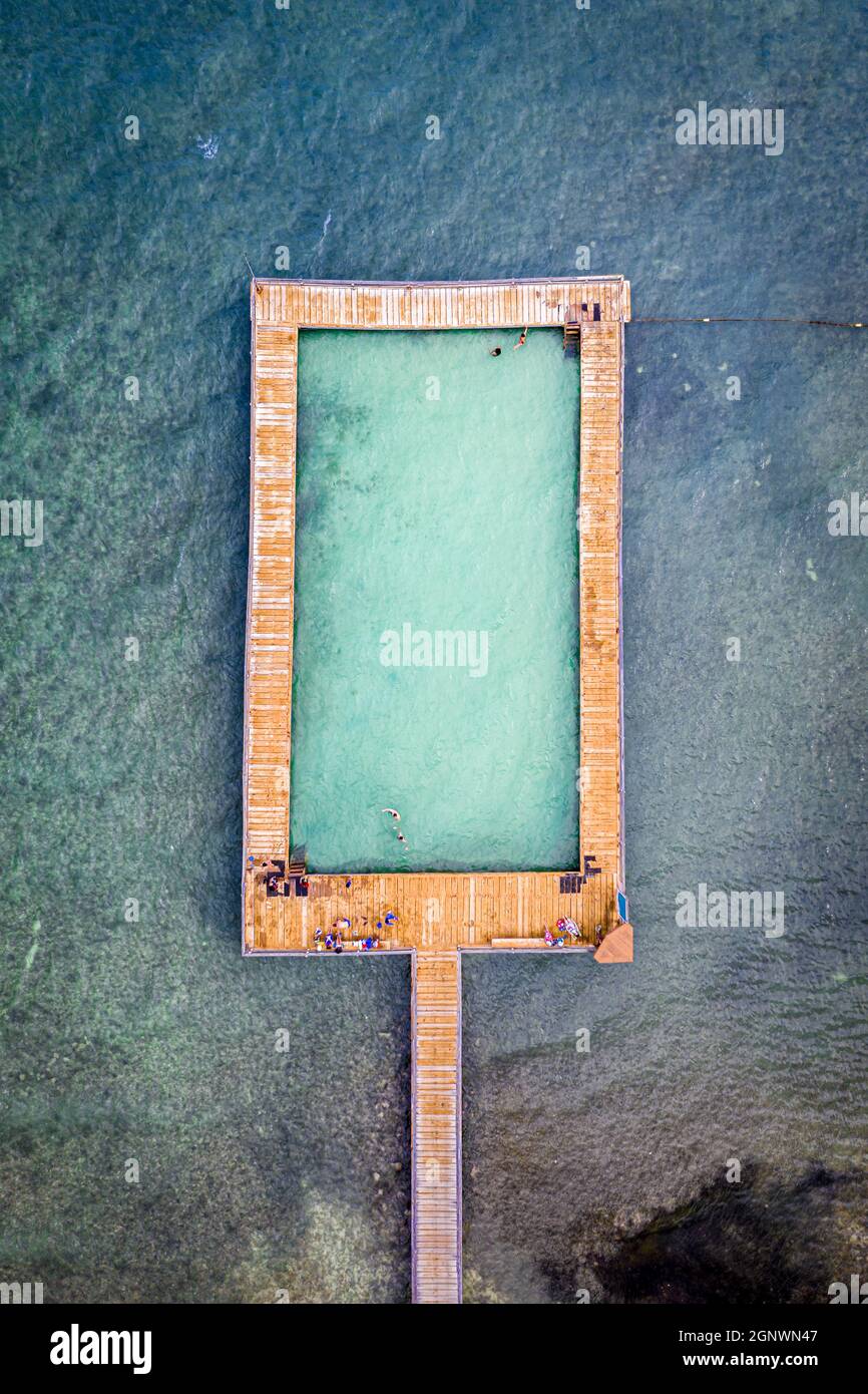 Aerial view of a rectangular pool in the middle of the sea with people ...
