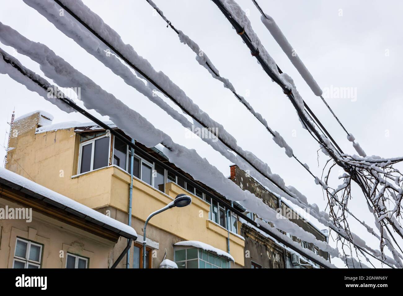 Electric cables and the buildings covered in snow Stock Photo - Alamy