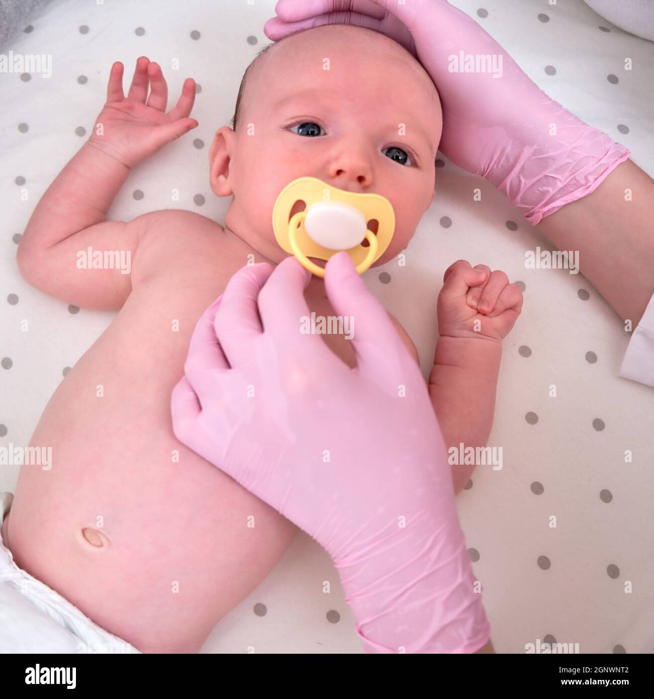 The doctor gives a pacifier to a newborn baby. Nurse in uniform soothes ...