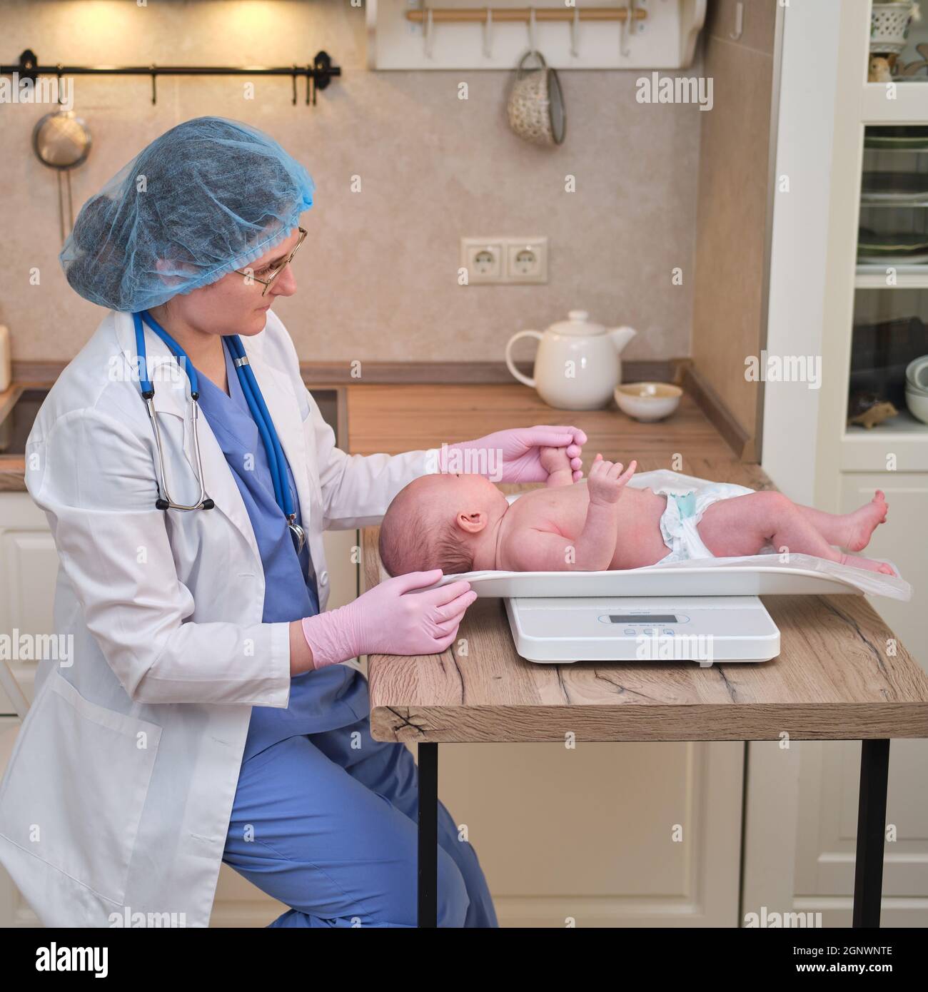 The doctor weighs a newborn baby on a scale. Uniformed nurse taking ...