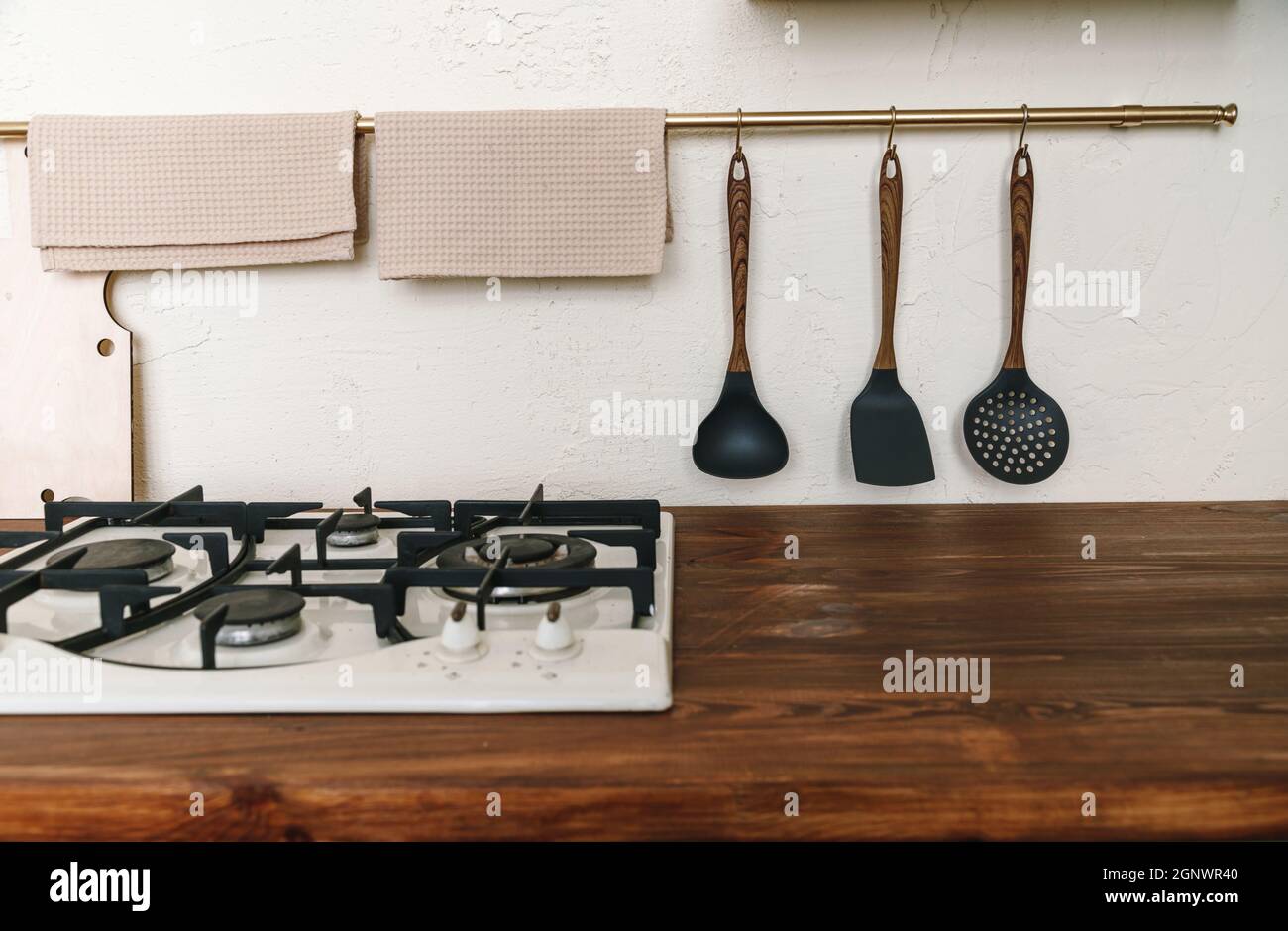 Kitchen wooden countertop with hob and kitchenware hanging on rail ...
